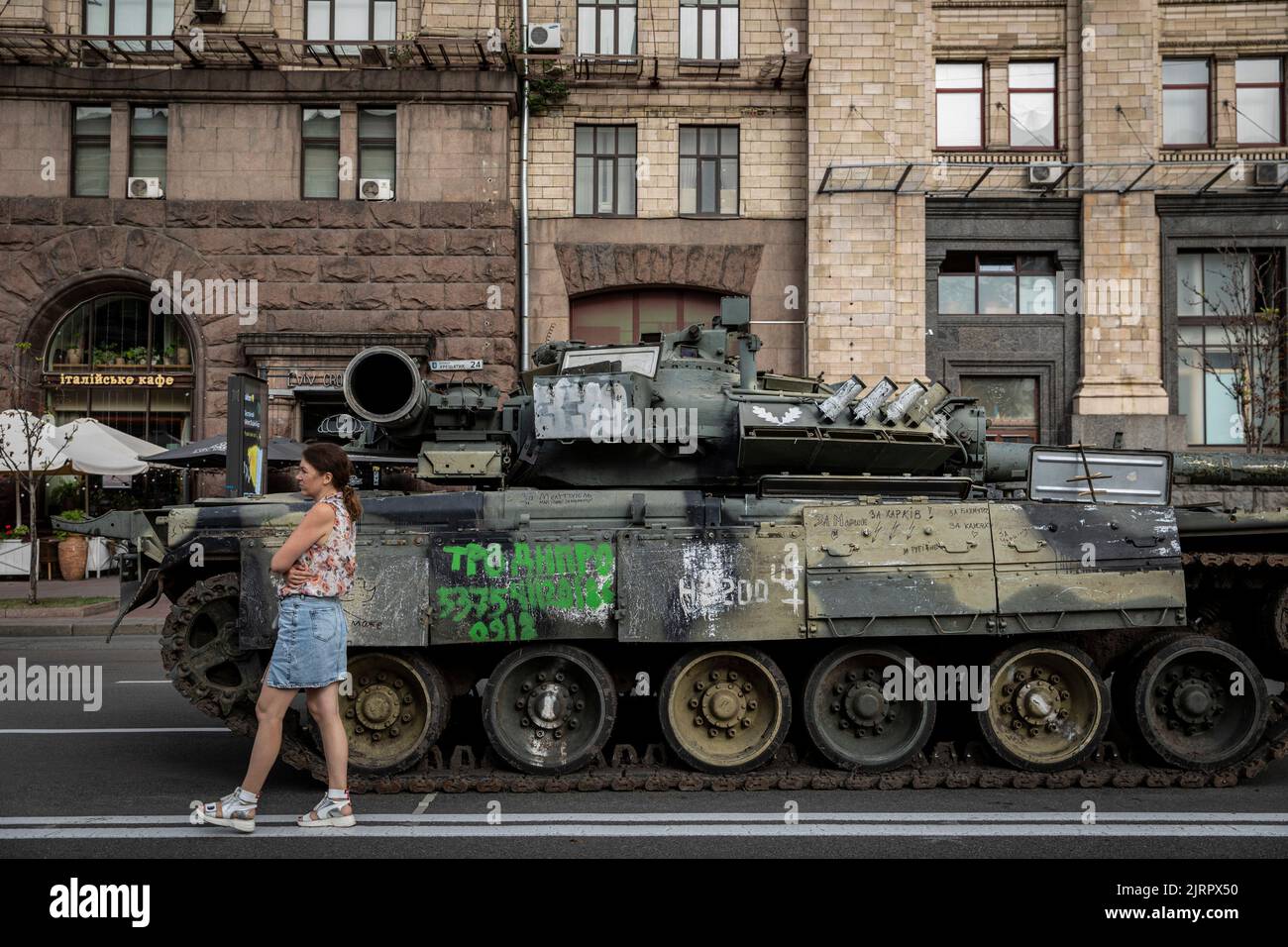 A woman walks past the wreckage of a destroyed Russian tank in Kyiv. As ...