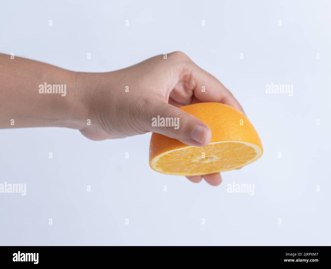 hand holding fresh raw citrus. hand squeezing a half orange fruit on ...