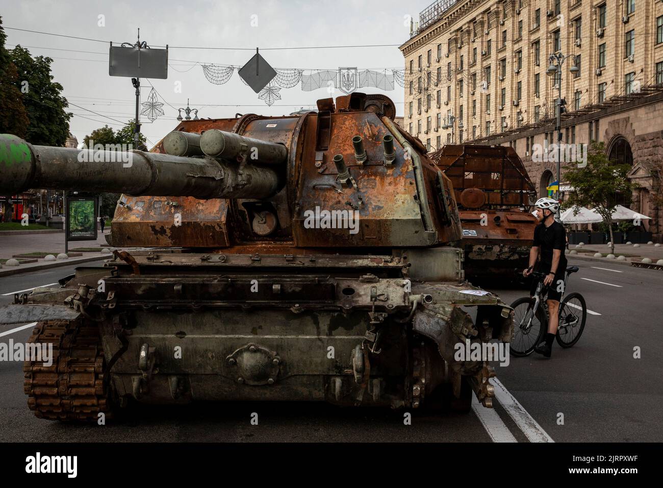 A man with a bicycle observes the wreckage of destroyed Russian tank in ...