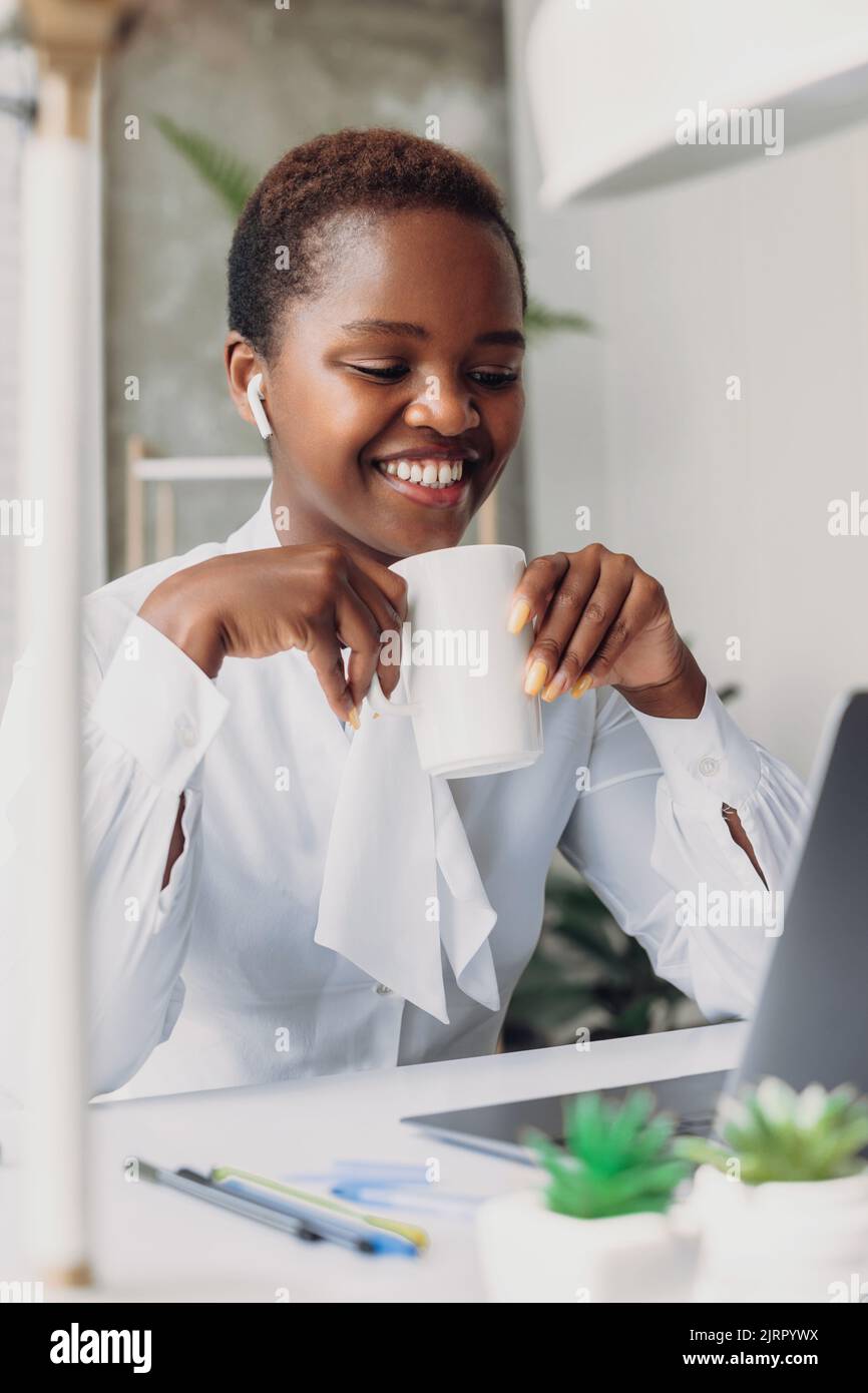 Smiling african-american businesswoman having coffee break, sitting at ...