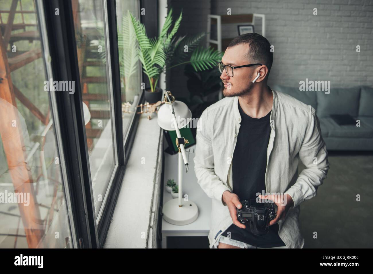 Portrait of caucasian male photographer looking away and keeping camera ...