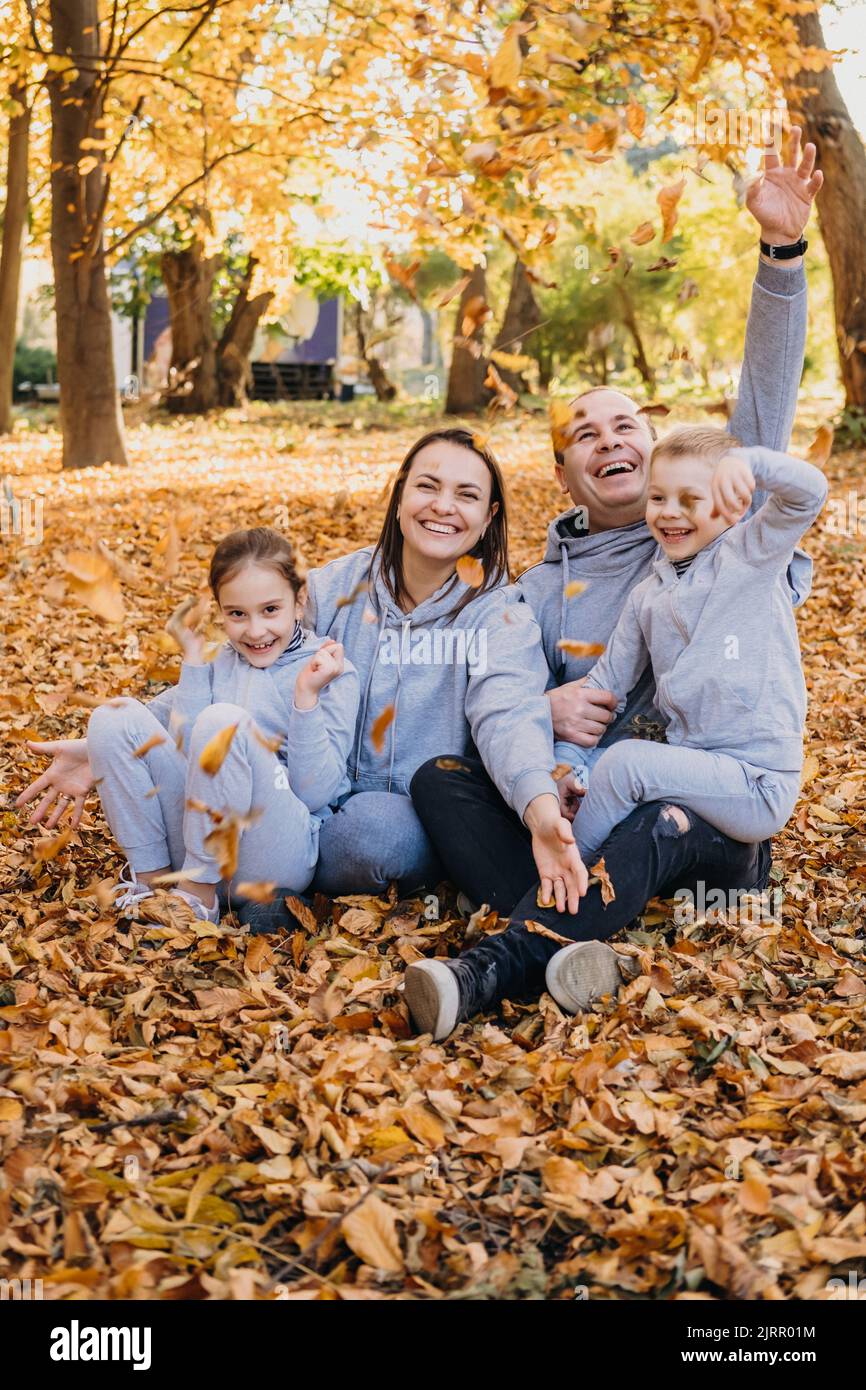 Portrait of a family posing together in an autumn city park, with ...
