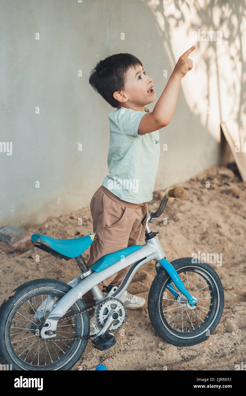 Excited caucasian little boy looking forward, pointing with finger while standing near the ...