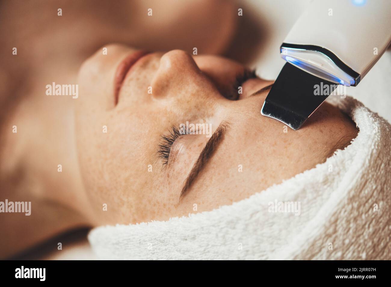 Caucasian freckled woman receiving face cavitation procedure at spa ...