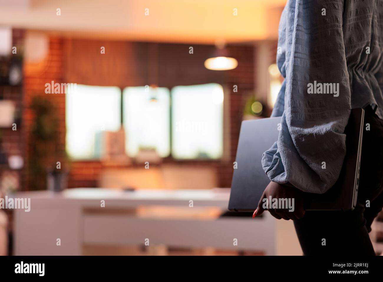 African american female student carrying laptop in home room with ...