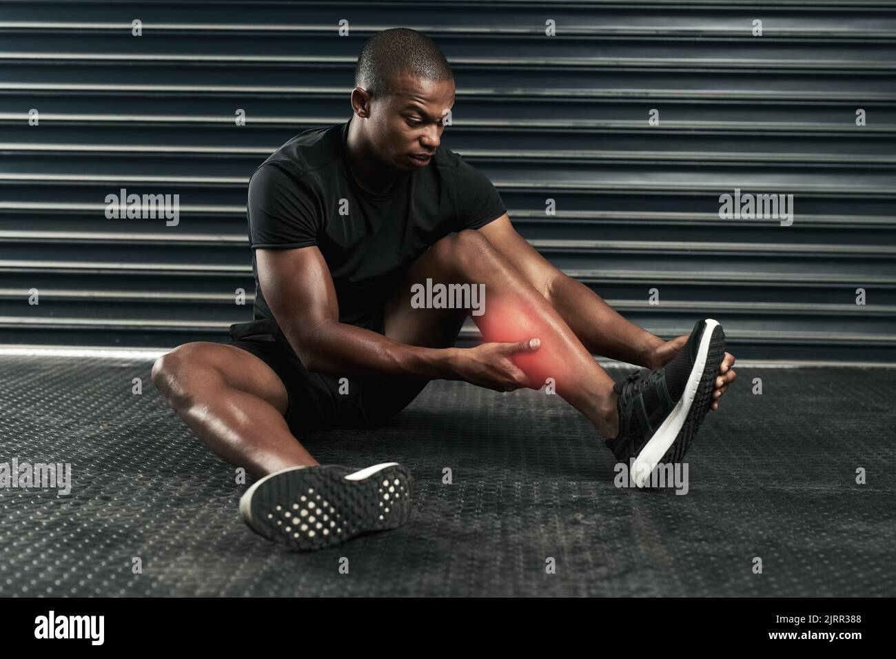 Checking on his calf injury. Studio shot of an athletic young man ...