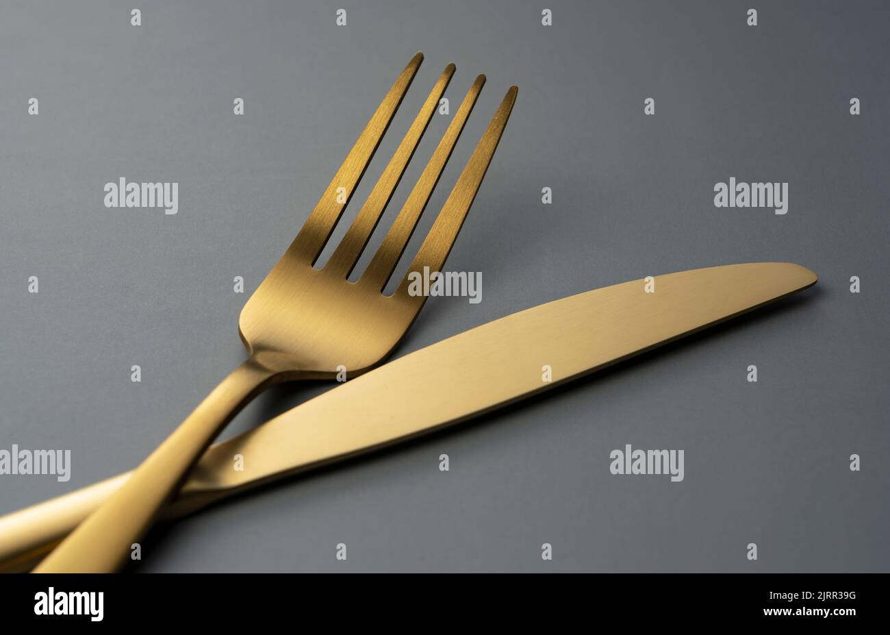 Gold knives and forks set against a black background. Beautiful gold ...
