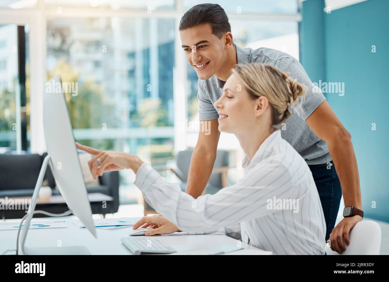 Manager consulting an employee about an online project on a computer in ...