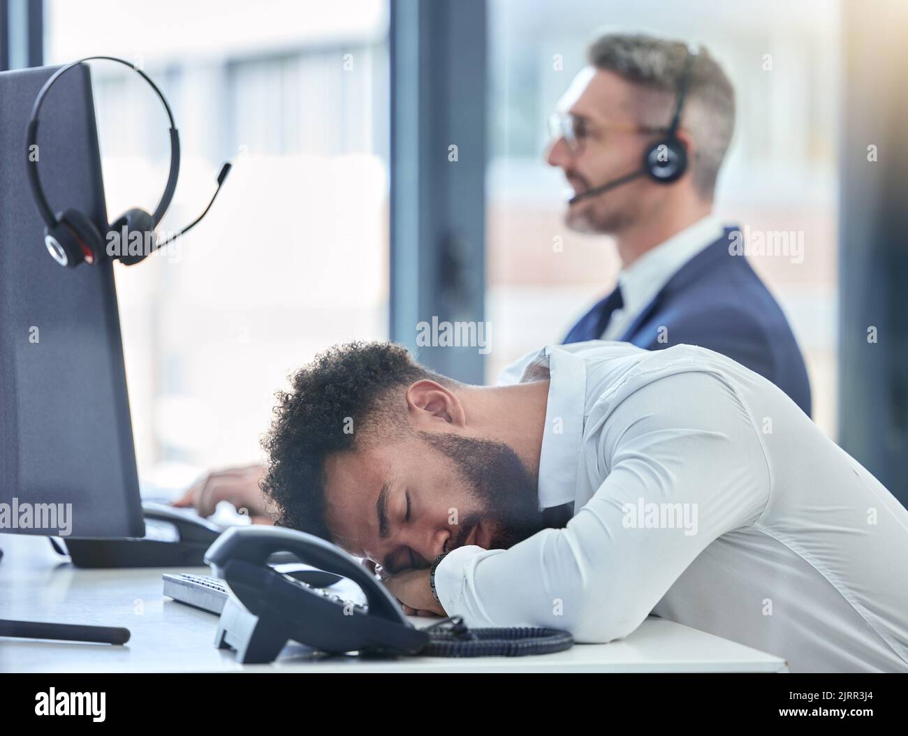 Lazy, sleeping and tired call center agent at his table or desk at work ...