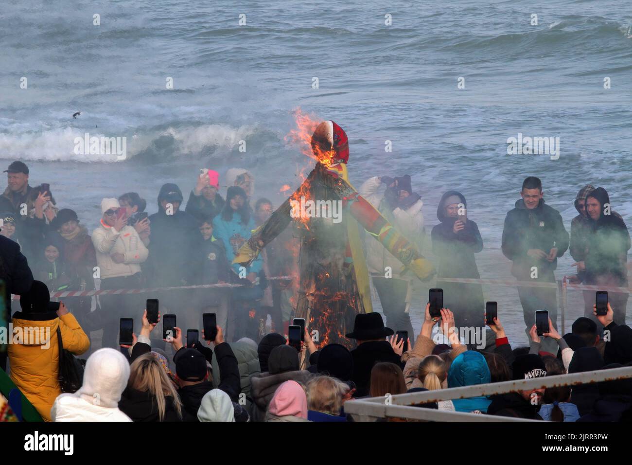 People are seen taking pictures of Winter's burning scarecrow ...