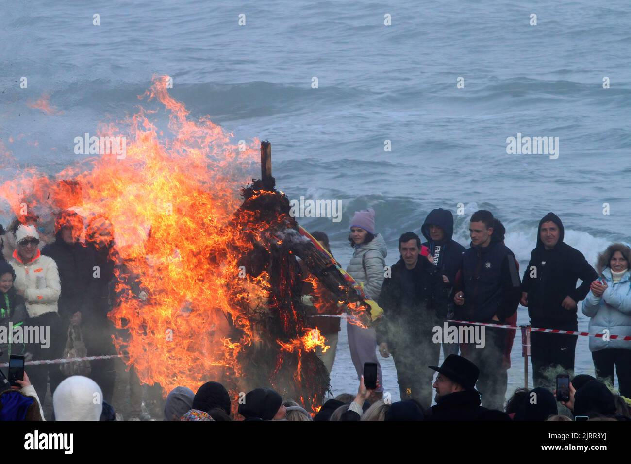 People are seen taking pictures of Winter's burning scarecrow ...