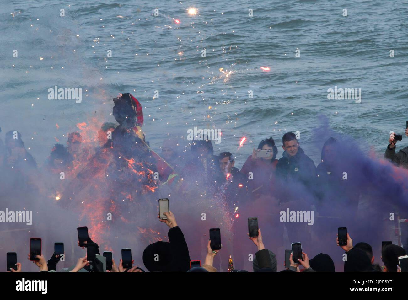 People are seen taking pictures of Winter's burning scarecrow ...