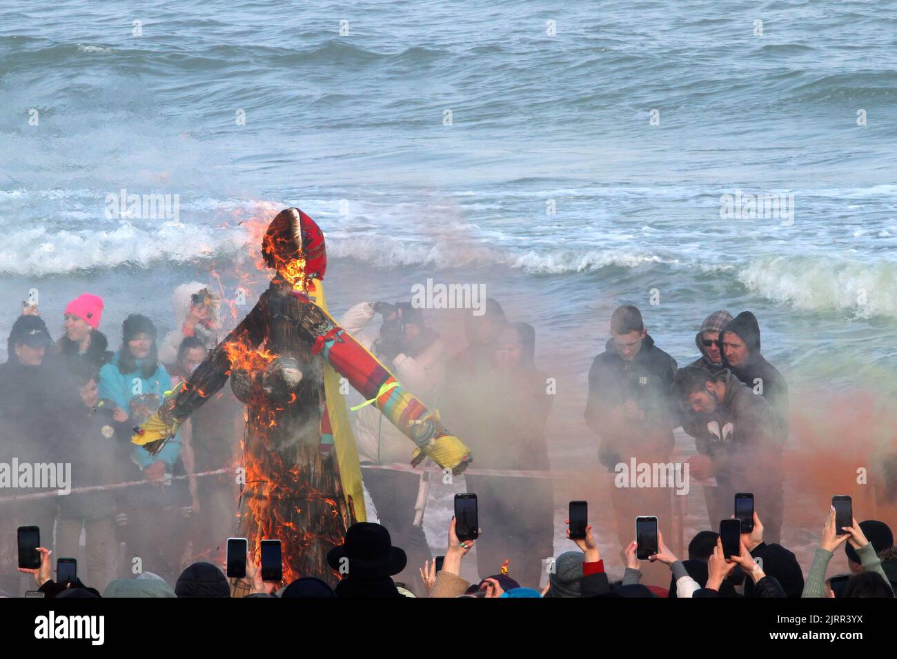 People are seen taking pictures of Winter's burning scarecrow ...