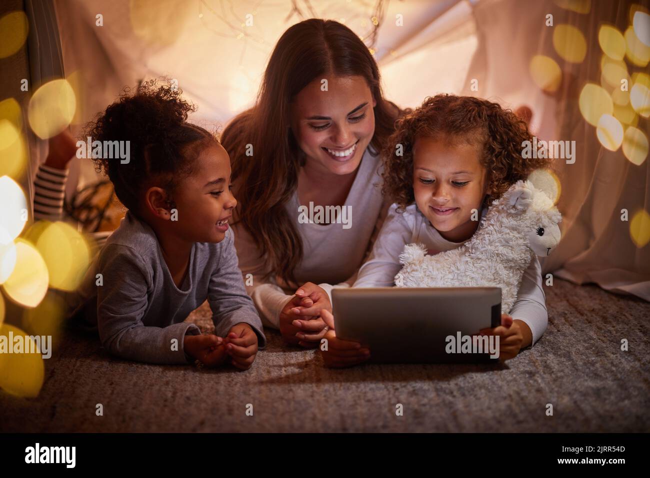 Mother and children live streaming on an app using a tablet in a tent ...