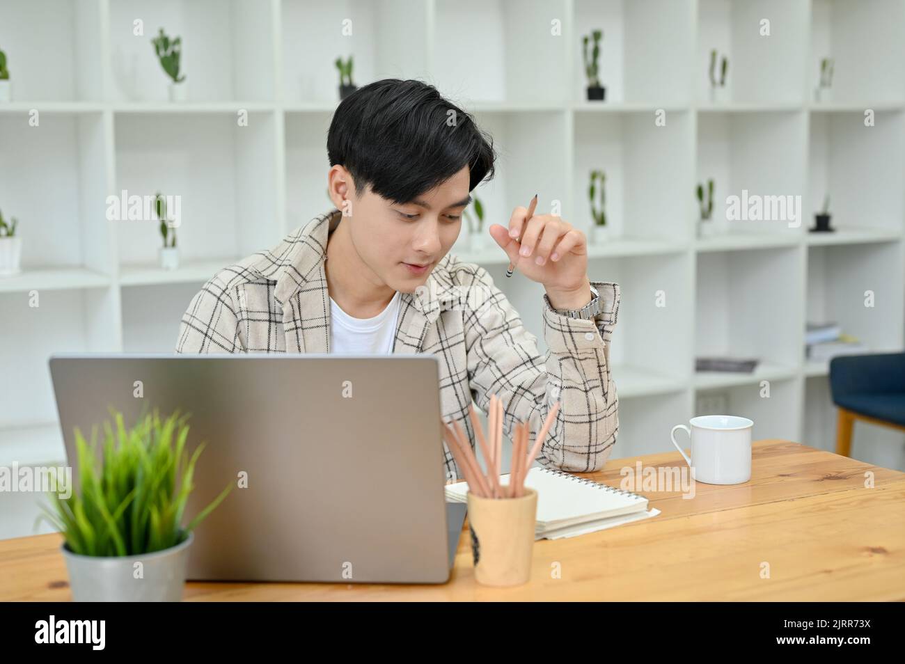 Concentrated young Asian male college student or freelancer working and ...