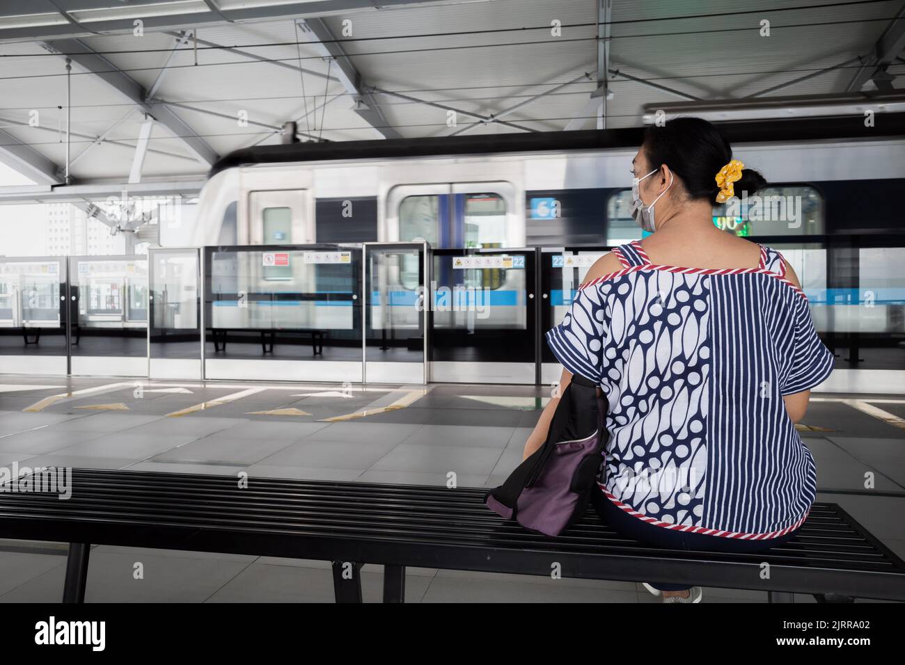 Southeast Asian woman sitting on a bench alone at subway station ...