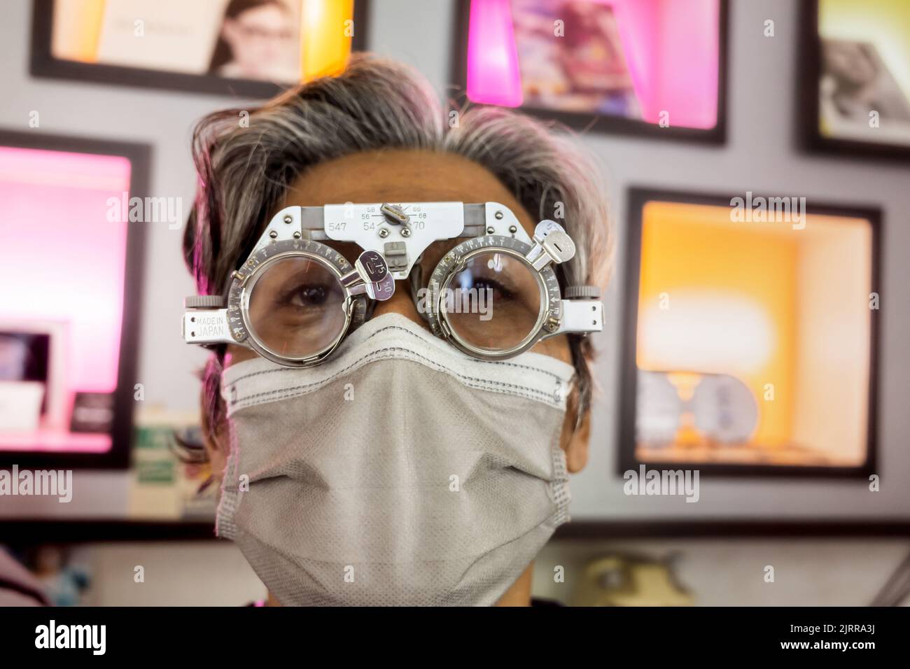 Mature Asian man wearing phoropter as eye test device for vision ...