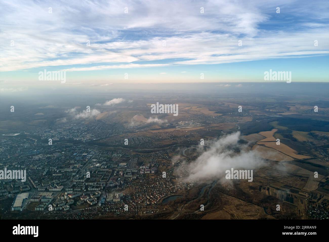 Aerial view from high altitude of distant city covered with puffy ...