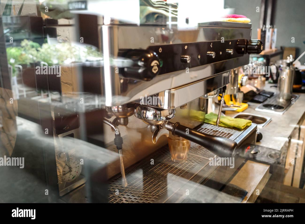 Coffee maker inside a cafe photograph from outside the window with some ...