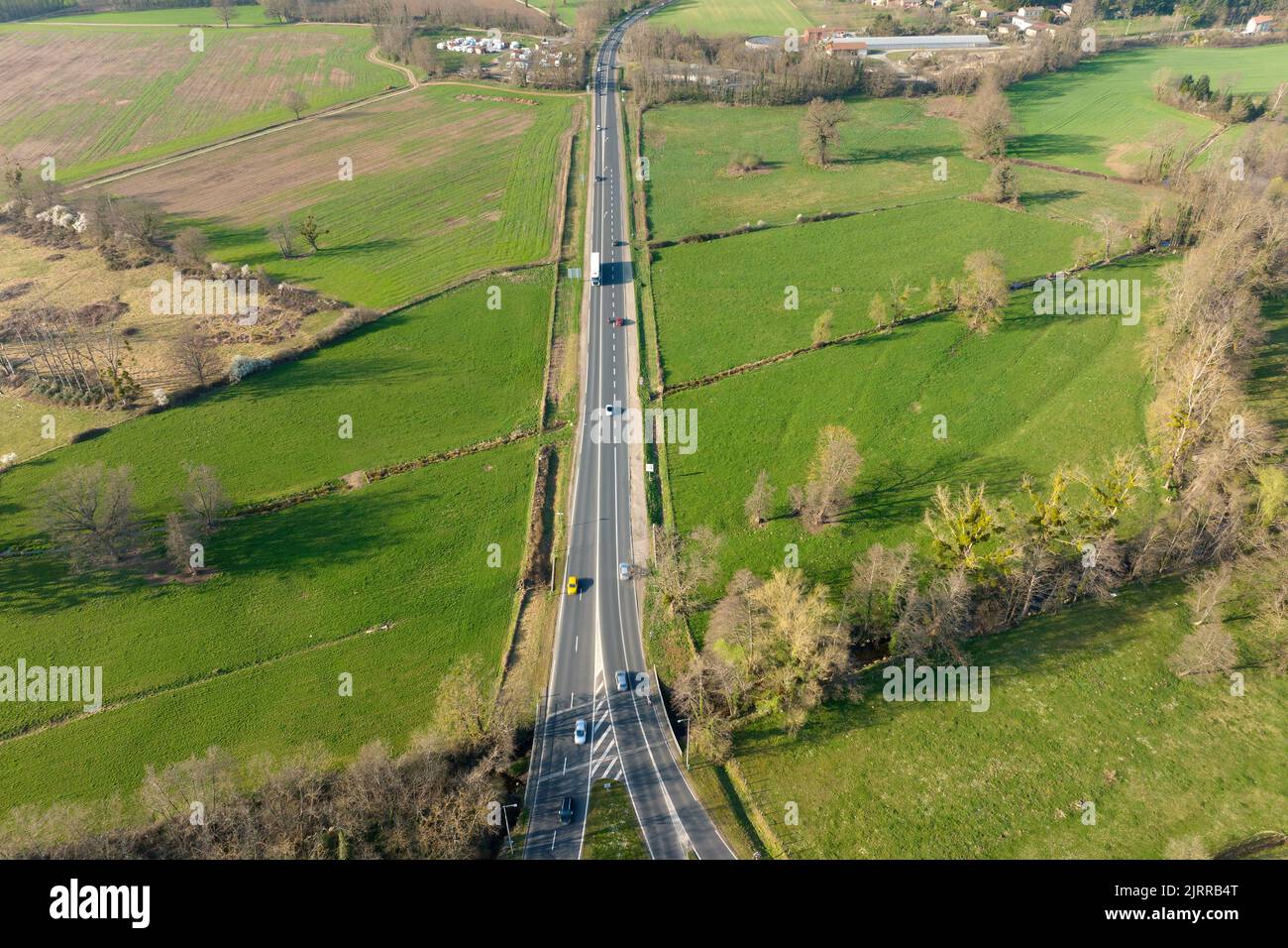 Aerial view of intercity road between green agricultural fields with ...