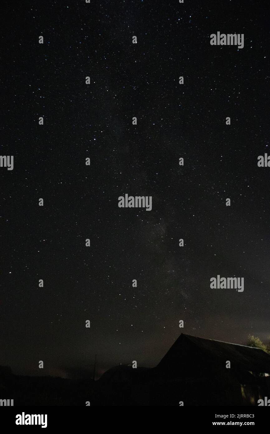 Starry sky with milky way above silhouette of old house in village ...