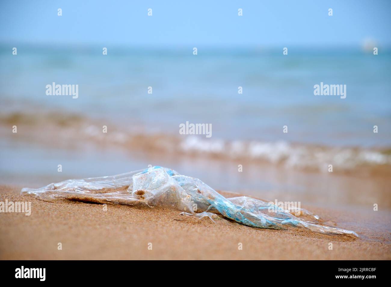 Left behind plastic bag garbage on sandy beach. Empty used dirty litter ...
