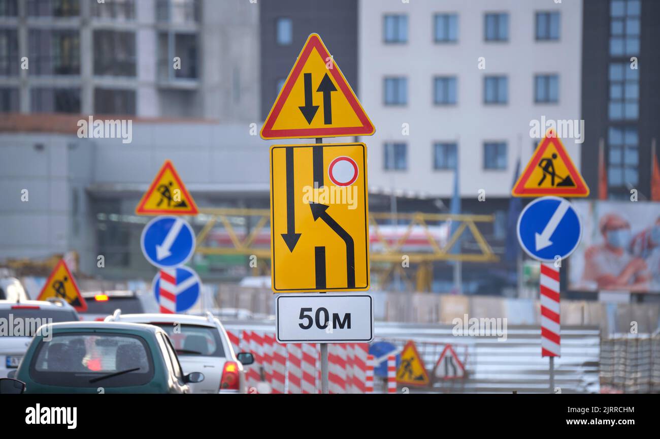 Roadworks warning traffic signs of construction work on city street and slowly moving cars Stock ...