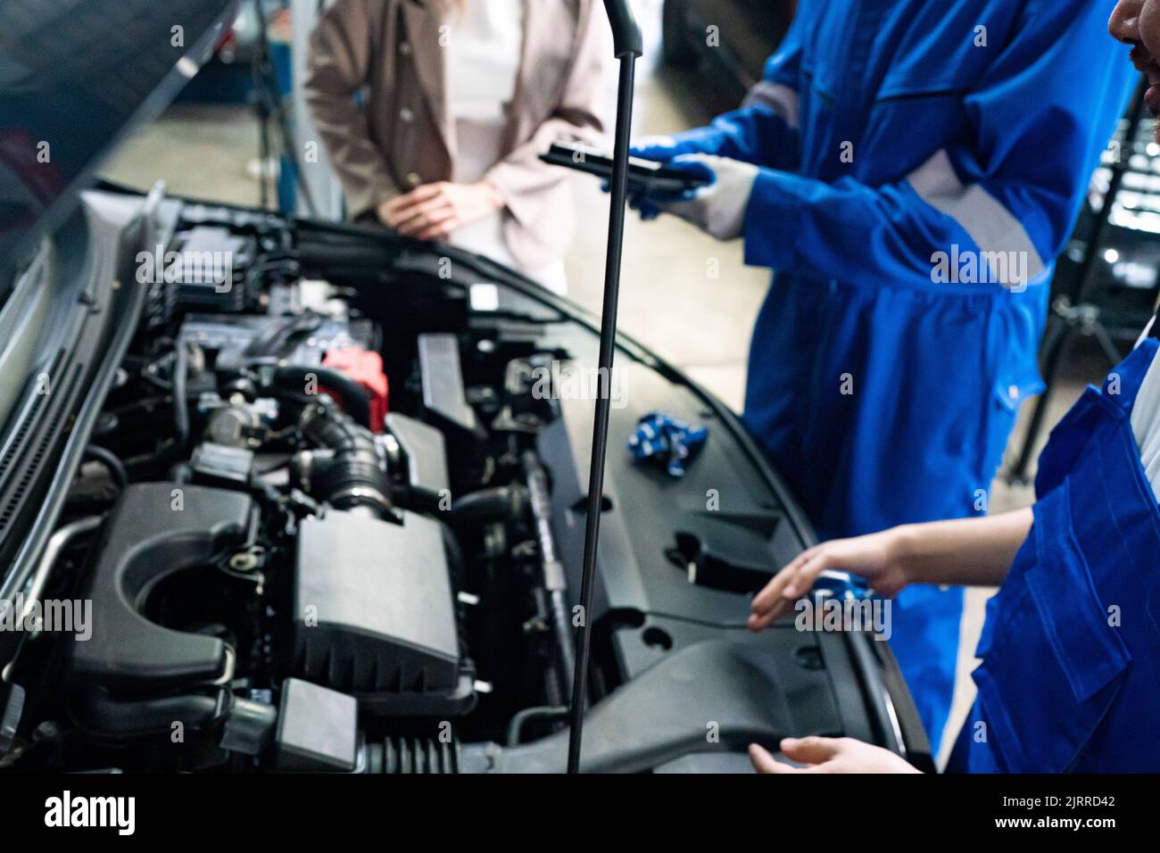Male car operator wearing blue overalls, gloves working under the hood ...