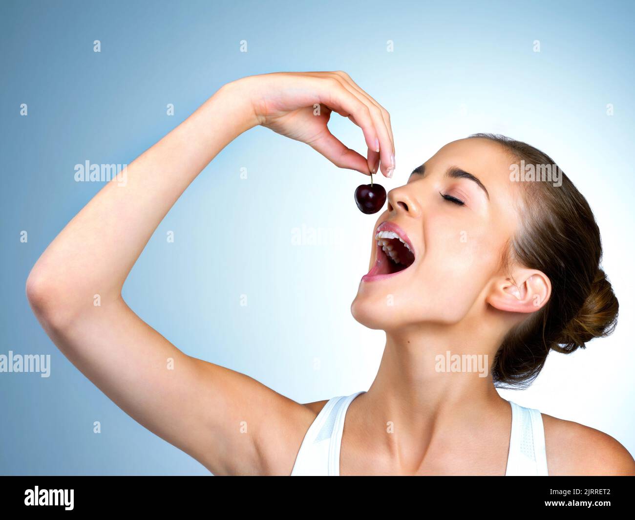 You are what you eat. a health-conscious young woman eating a cherry in ...