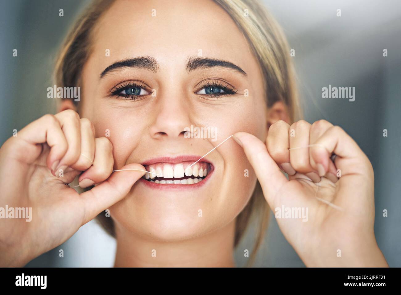You should floss at least once a day. Portrait of an attractive young ...