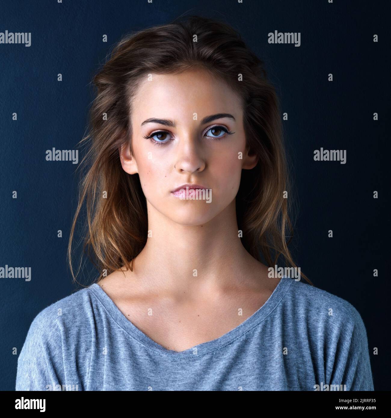 Her expression is unreadable. Studio shot of an expressionless teenage ...