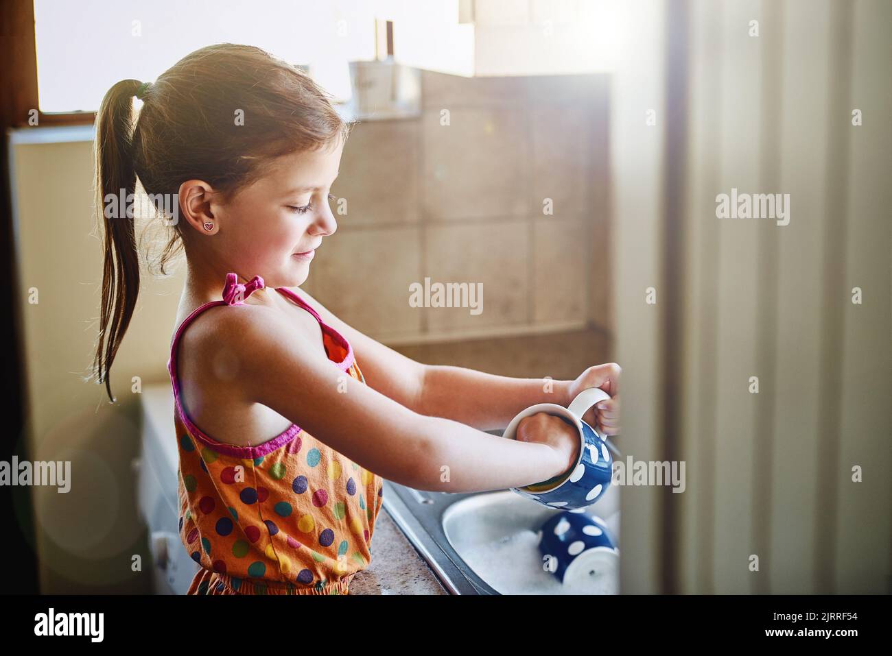 Keeping things clean and tidy. a little girl washing dishes at home ...