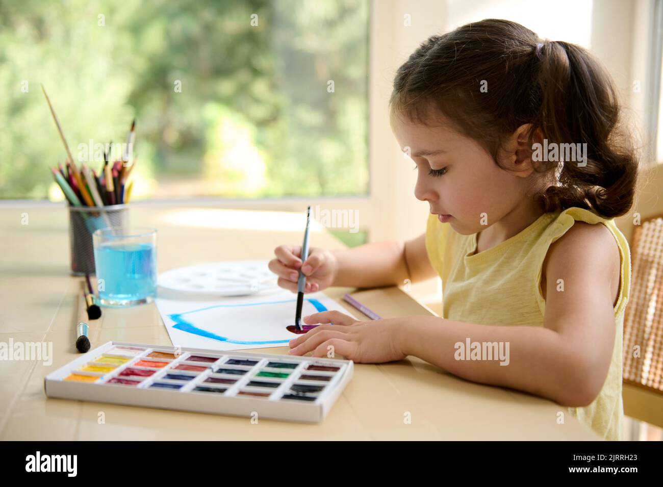 Little girl drawing picture while learning watercolor painture ...