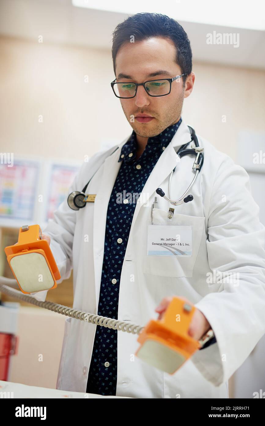 Ready to restore a healthy heartbeat. a doctor using a defibrillator in ...