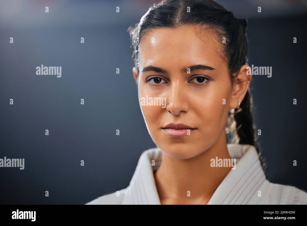 Portrait of female athlete, serious, and in karate gear staring ahead ...