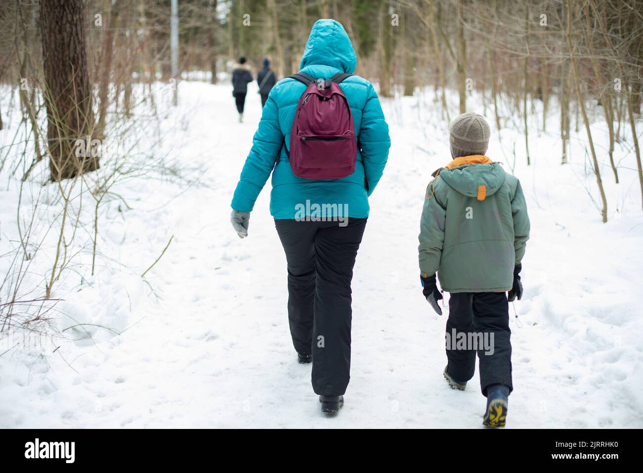 Mother and son in park. People walk in winter along path in park ...