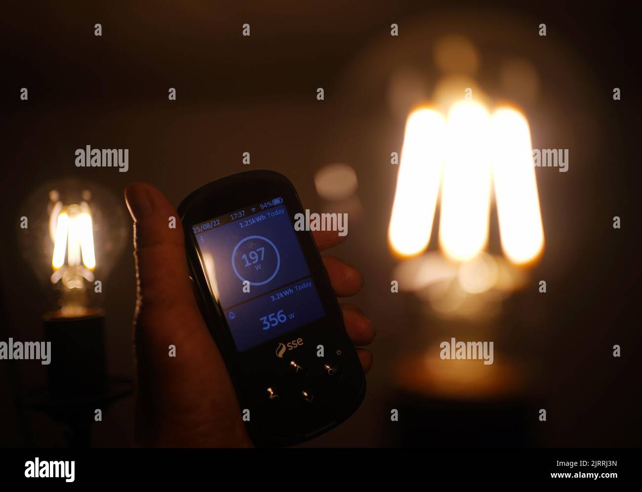 A handheld SSE smart meter for household energy usage is held next to ...