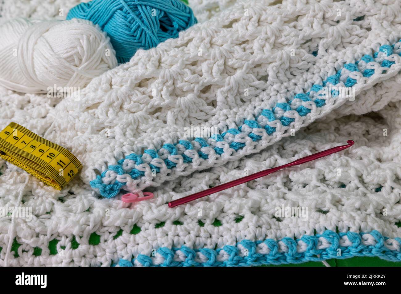 Unfinished white crochet blanket, blue details on edges, stitch marker ...