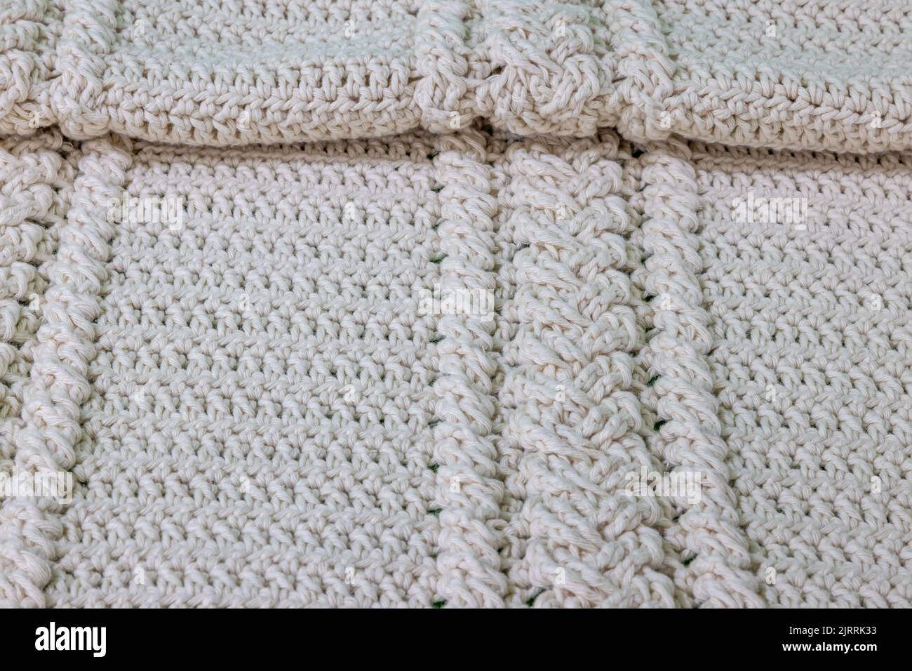 Top view of a crochet blanket in beige cotton yarn folded at the top ...