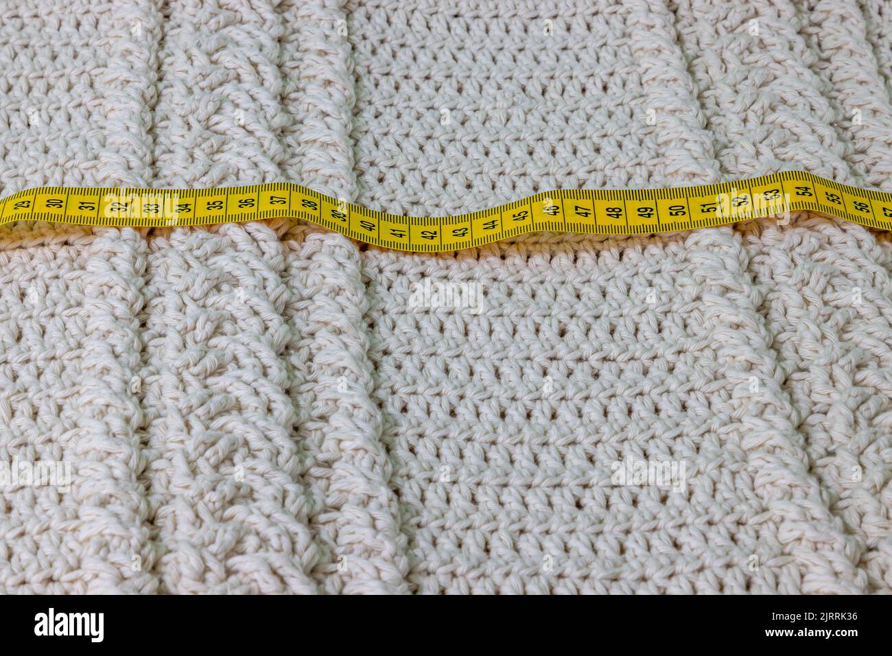 Yellow measuring tape on the surface of a crochet blanket finished in ...