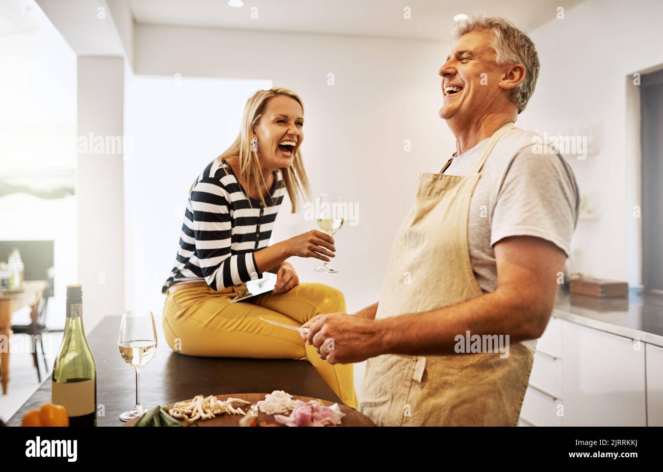 Happy and carefree couple cooking dinner laughing and enjoying the ...