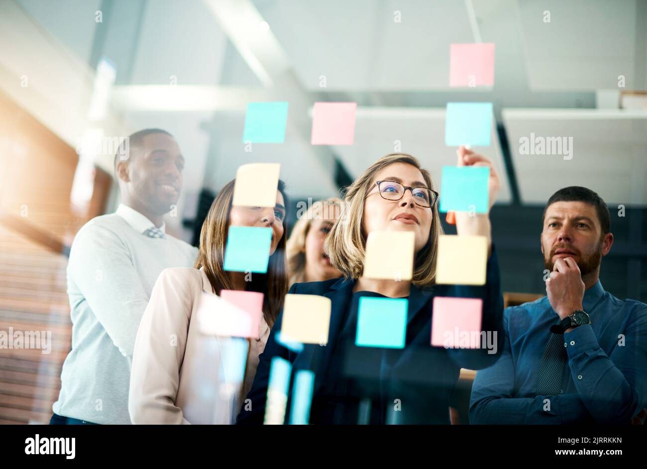 Group of business people talking about the notes on the glass wall in ...