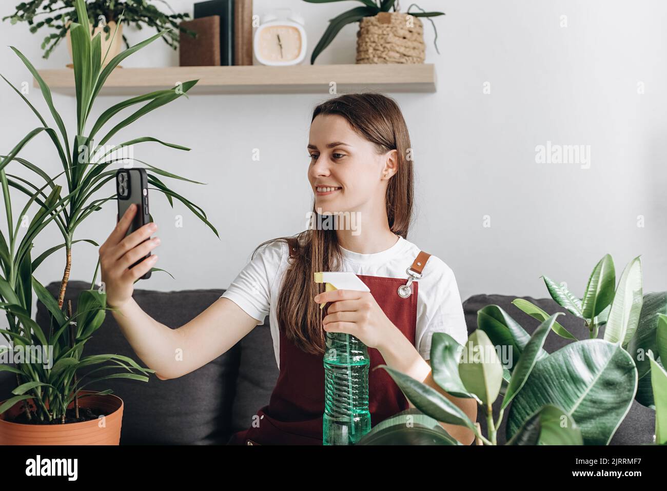 Smiling gardener girl enjoying pleasant conversation using mobile web ...