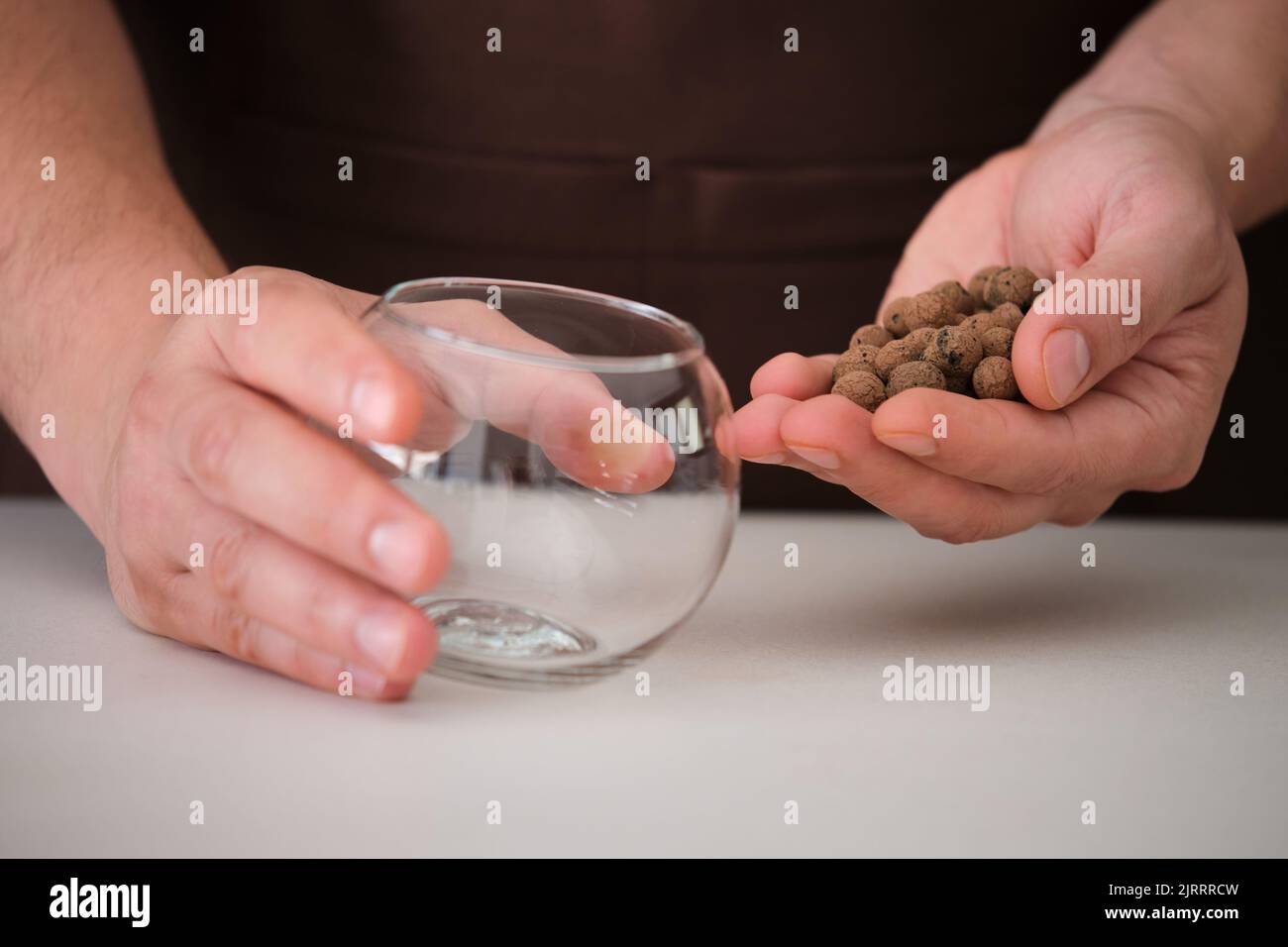 Man's hands holding lightweight expanded clay aggregate and a crystal ...