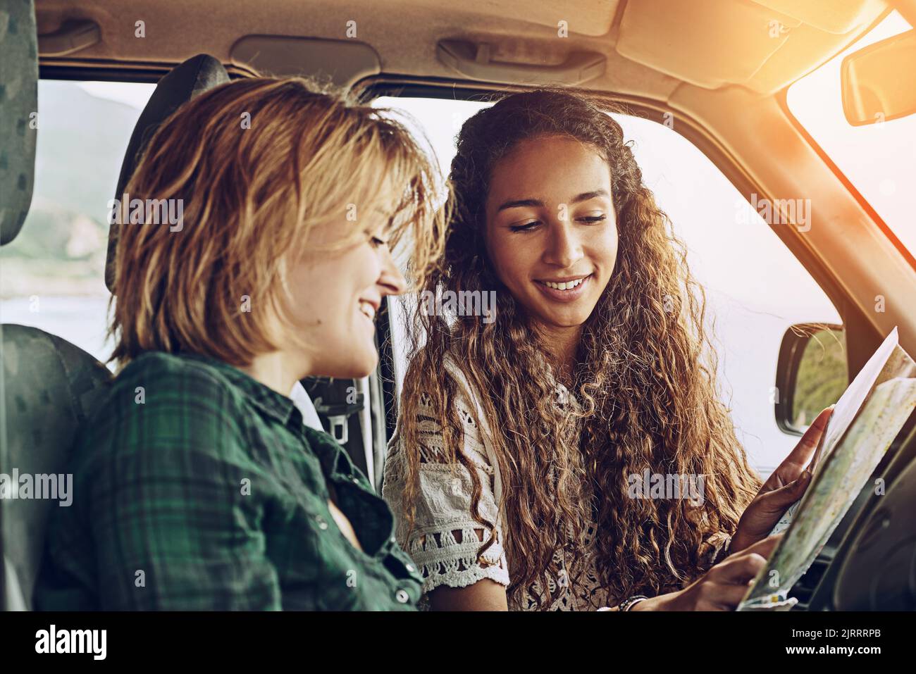 Mapping out their adventure. two young friends reading a map while on a ...