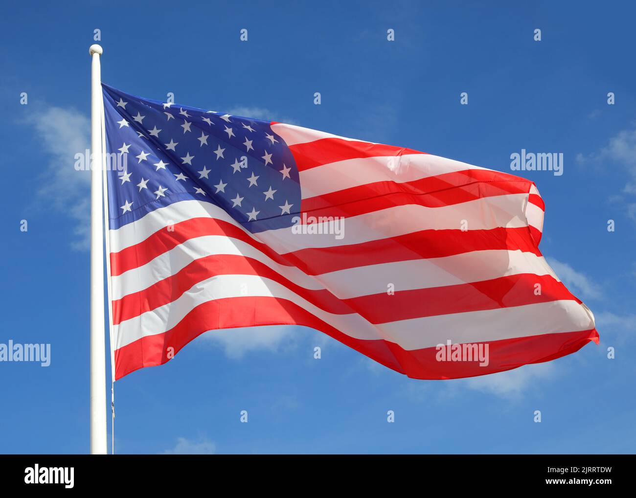 Waving big flag of United States of America on blue sky background ...