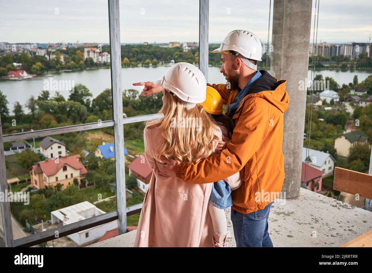 Back view of parents with daughter standing inside apartment building ...