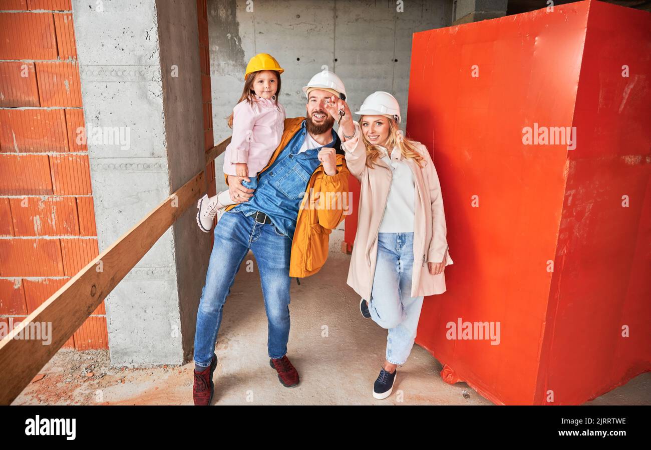 Man holding daughter and smiling. Happy couple real estate house buyers demonstrating keys from ...