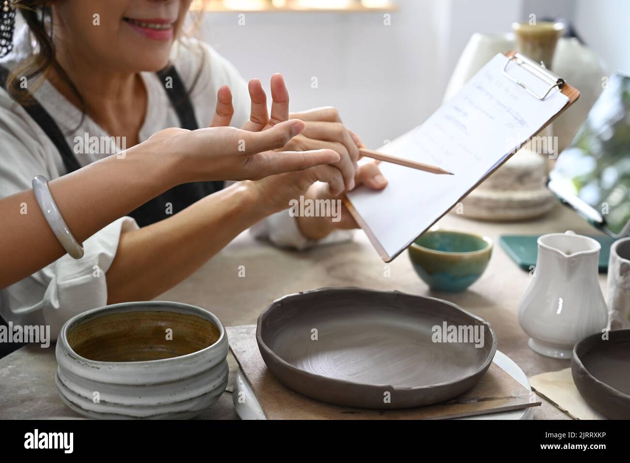 Female pottery shop owner checking purchase order, preparing product ...