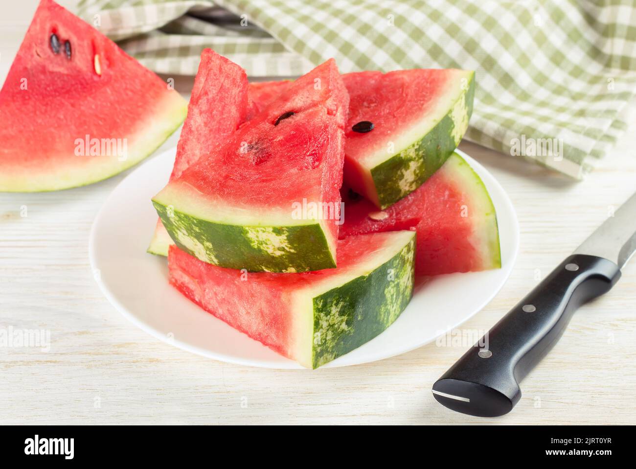 Triangle slices of watermelon on the plate on white wooden background ...